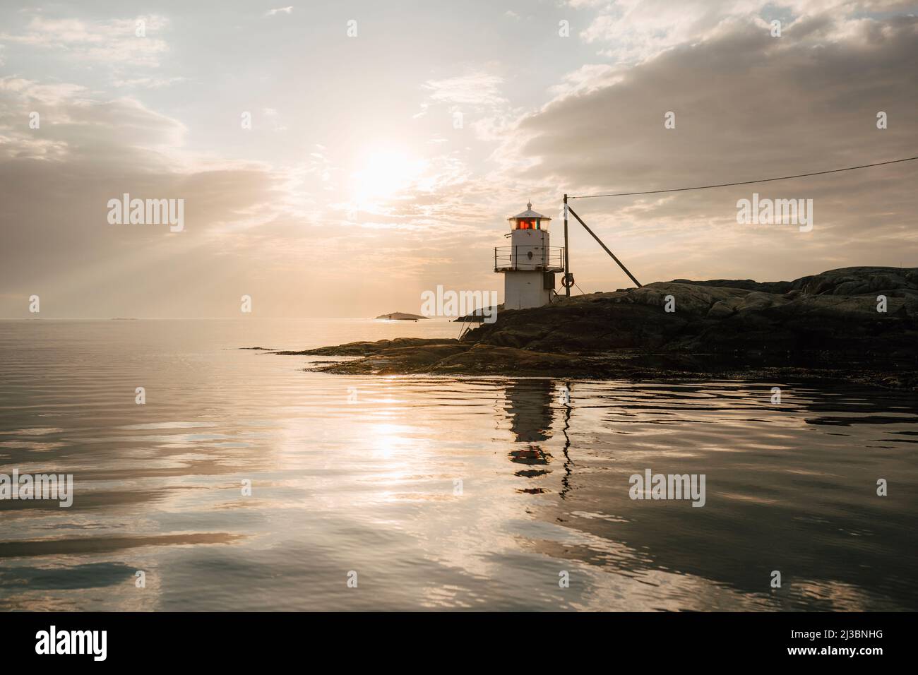 Lighthouse and calm sea at sunset Stock Photo - Alamy