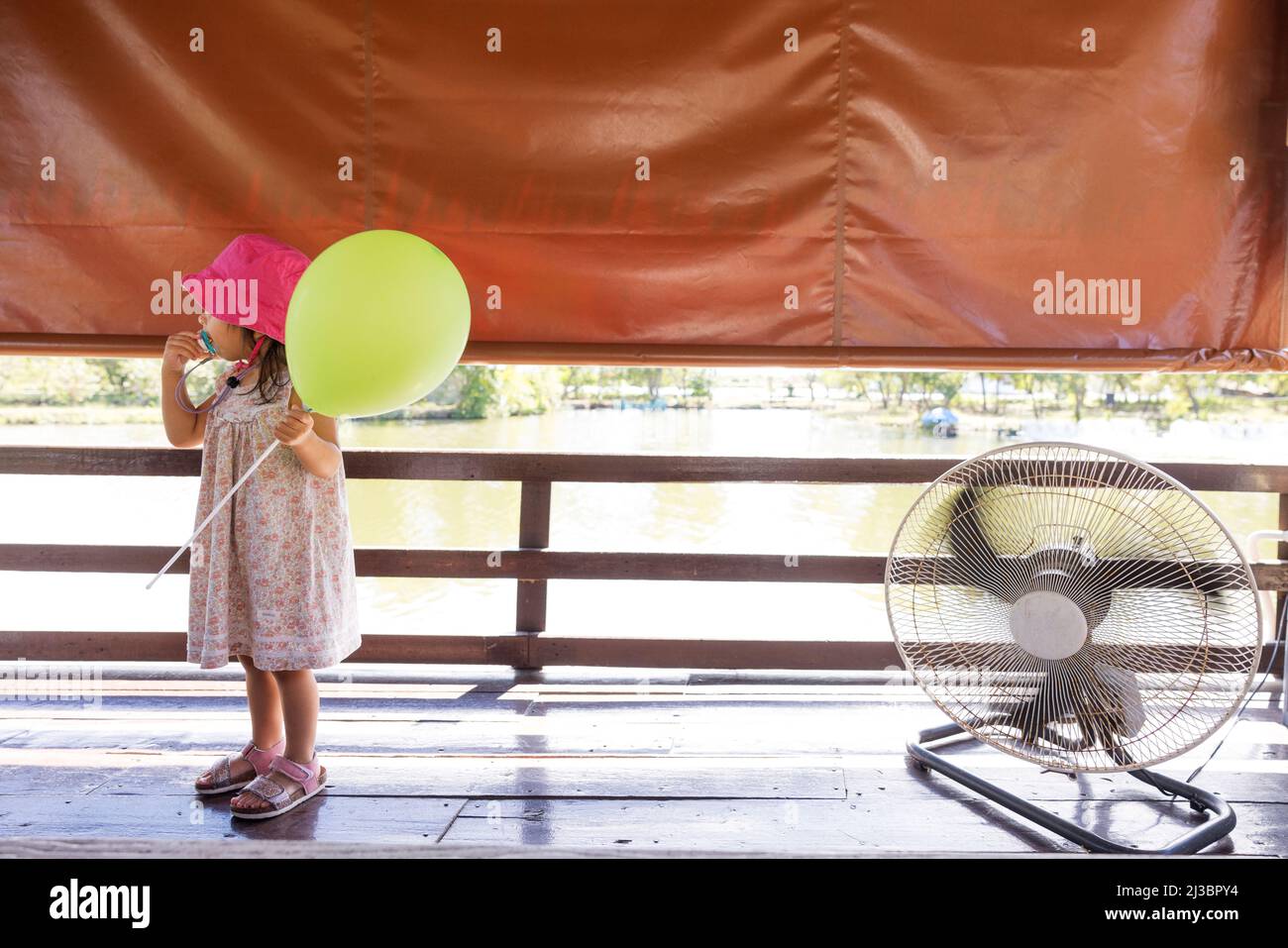 Girl holding balloon next to electric fan Stock Photo - Alamy