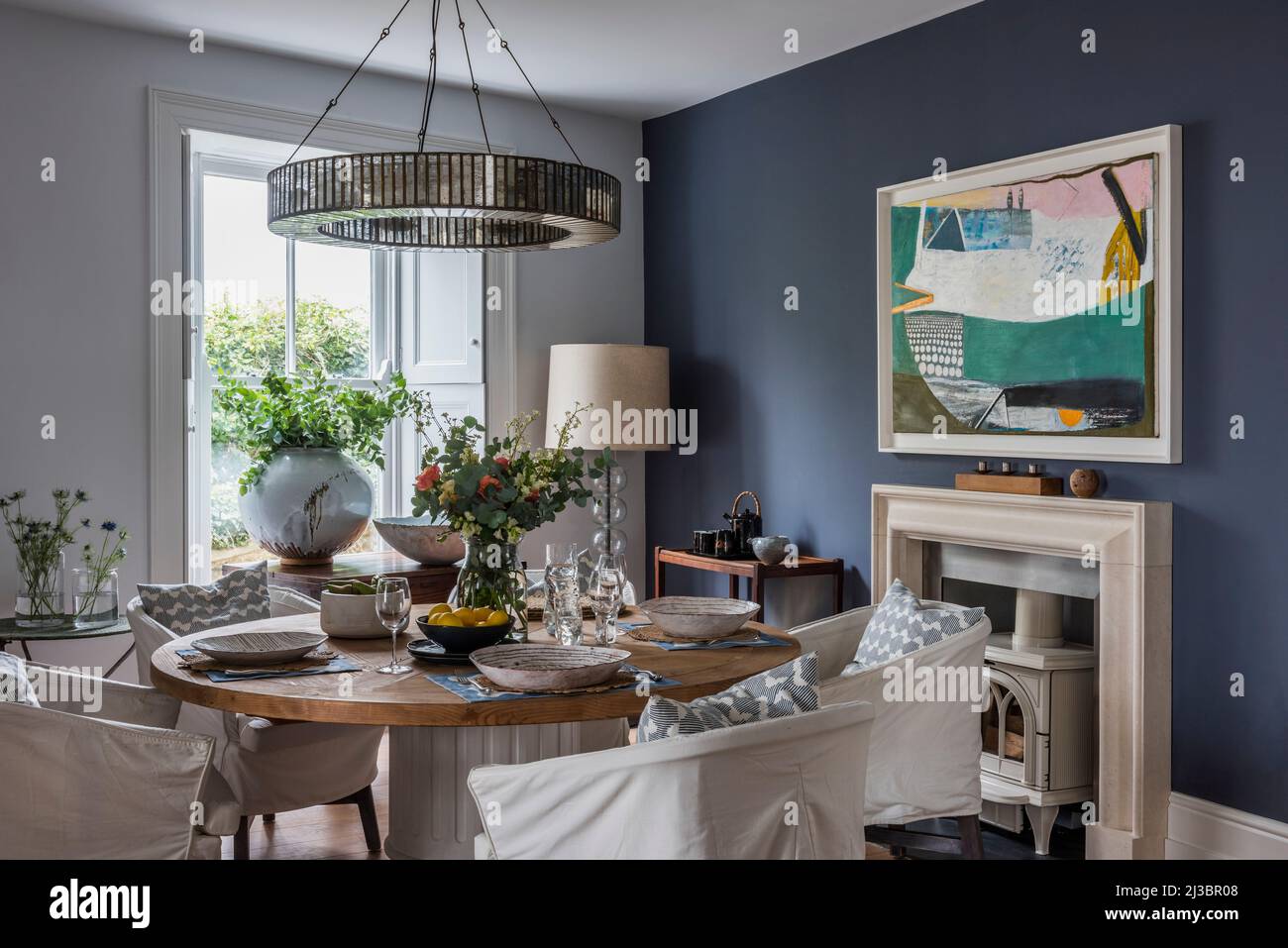 Mirrored pendant above wooden dining table with painting by Matthew ...