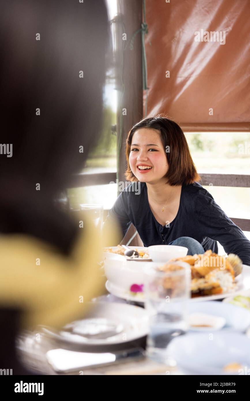 Smiling teenage girl sitting at dining table outdoors Stock Photo - Alamy
