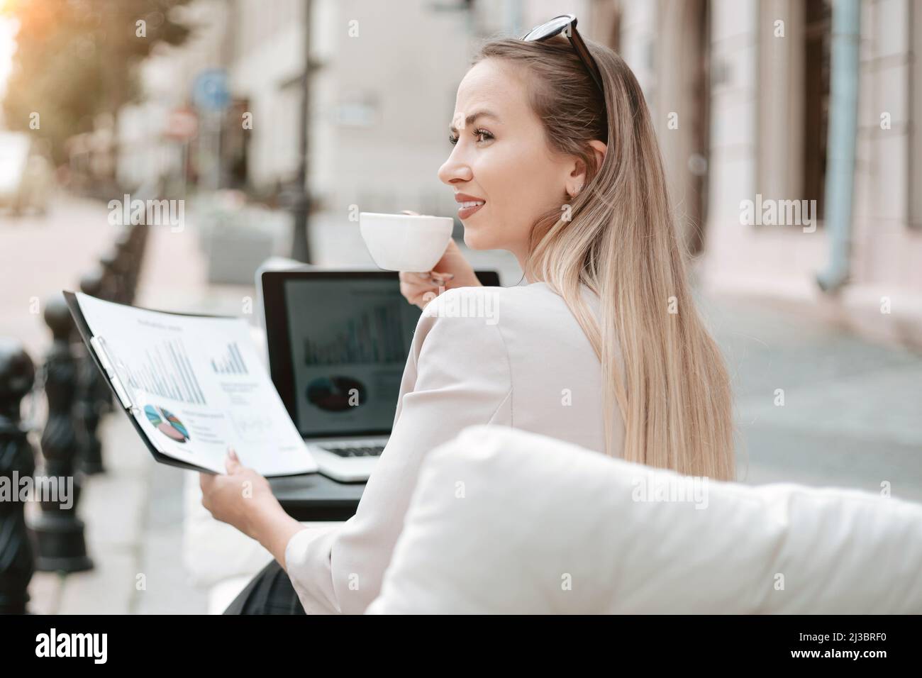 business woman works on a laptop while sitting at a table in an outdoor ...