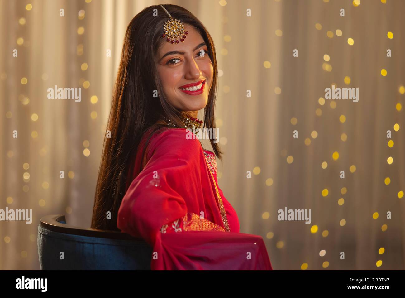 Young girl looking back at camera with smile while sitting on chair ...