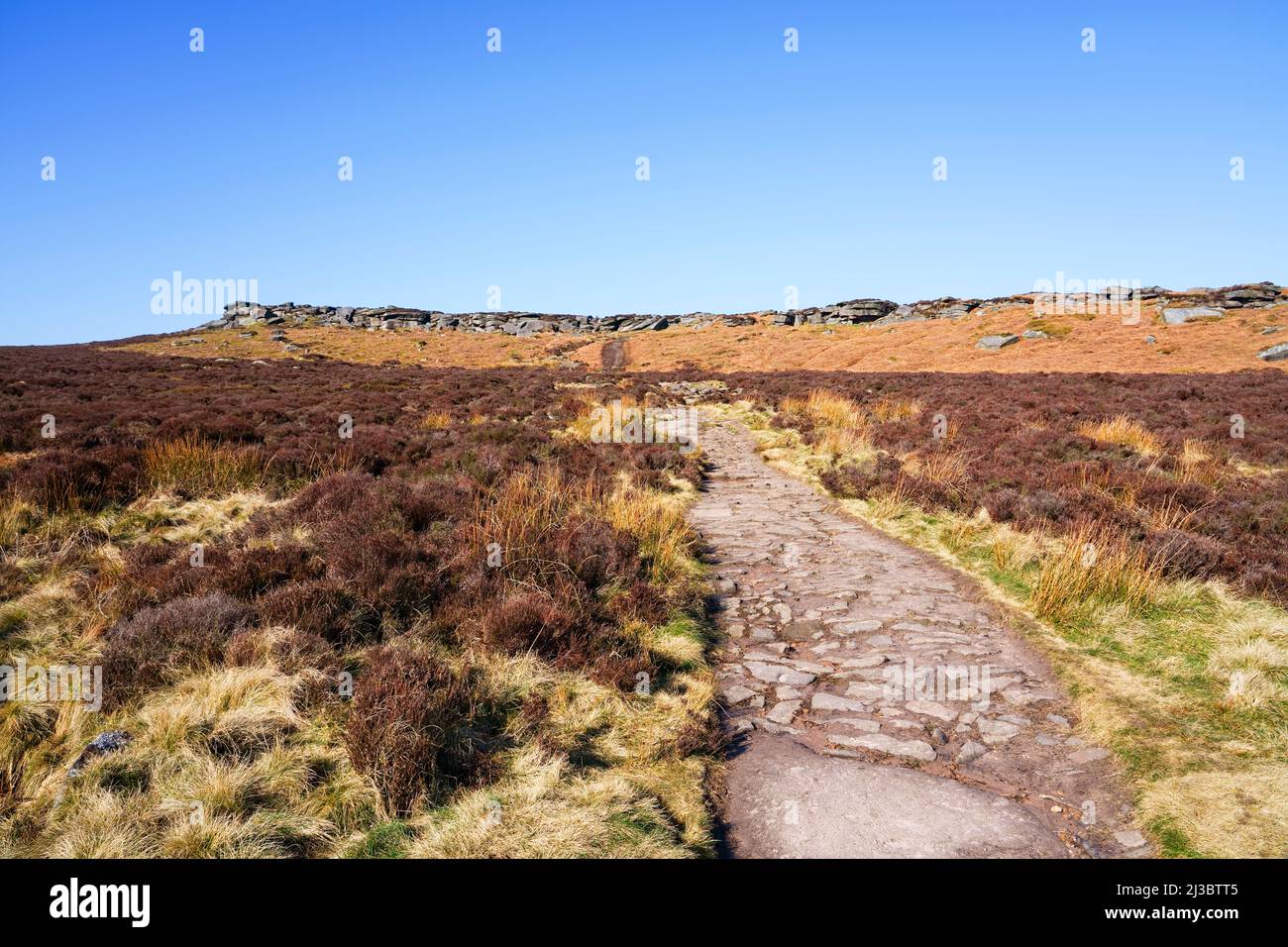 Narrow gritstone covered path leads across dry moorland and up to the ...