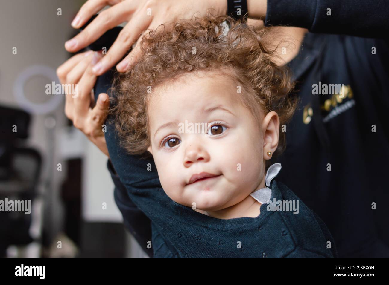 portrait little baby looking forward in the living room while her ...