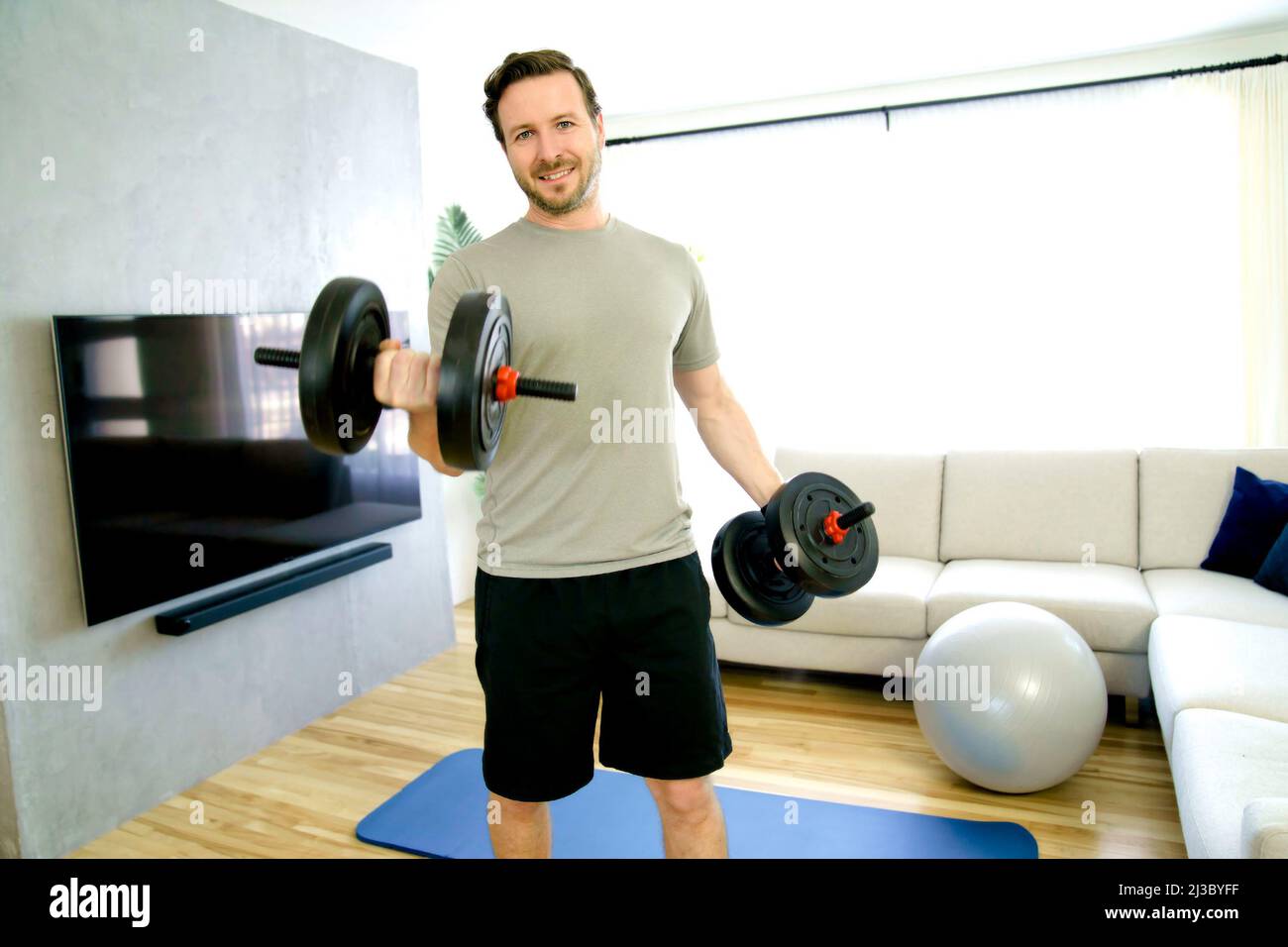 Attractive Fit man Exercise at home on the living room with dumbell on ...