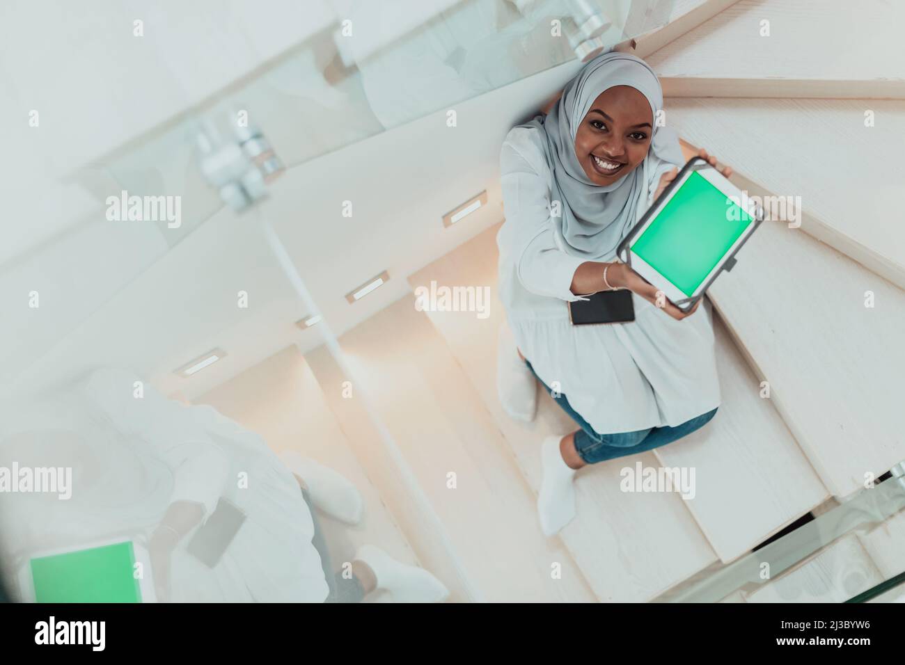 Young african modern muslim woman using tablet computer while sitting ...