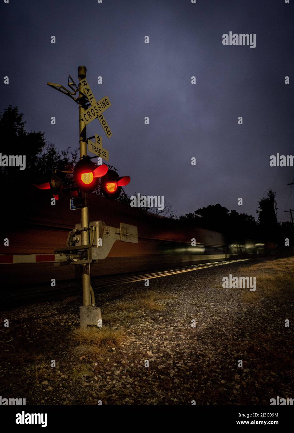 A vertical shot of a railroad crossing gate and a train in motion at ...