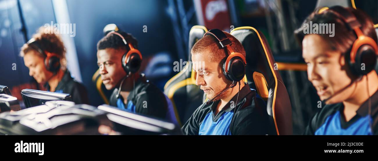 Team of four professional cybersport gamers wearing headphones ...