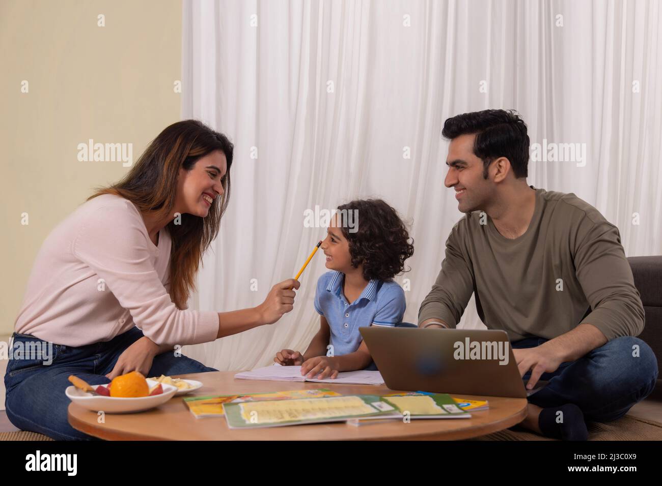 Mother kidding with her son and father using laptop Stock Photo - Alamy