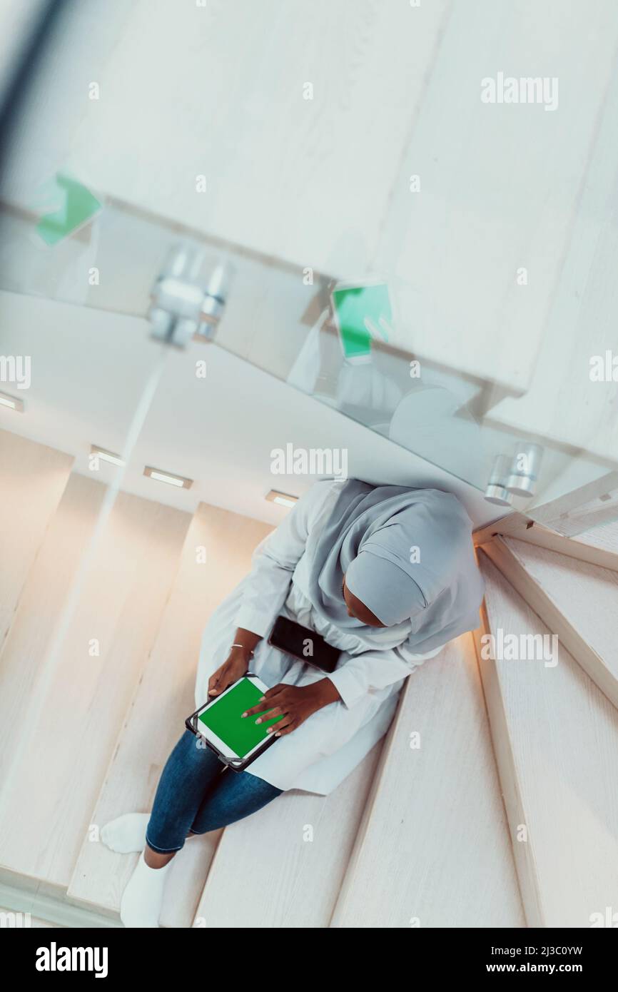 Young african modern muslim woman using tablet computer while sitting ...