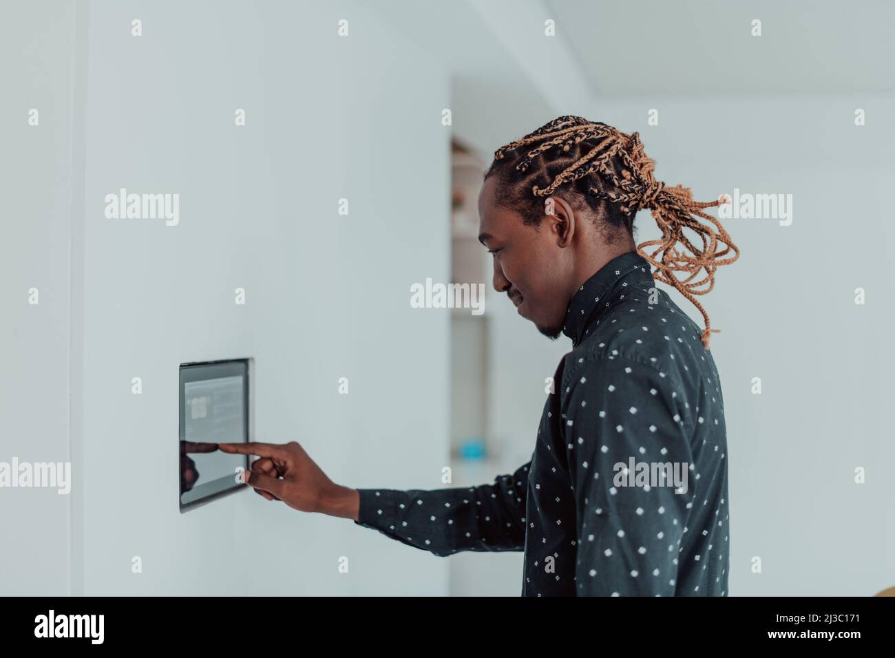 Smiling African American man using modern smart home system, controller ...