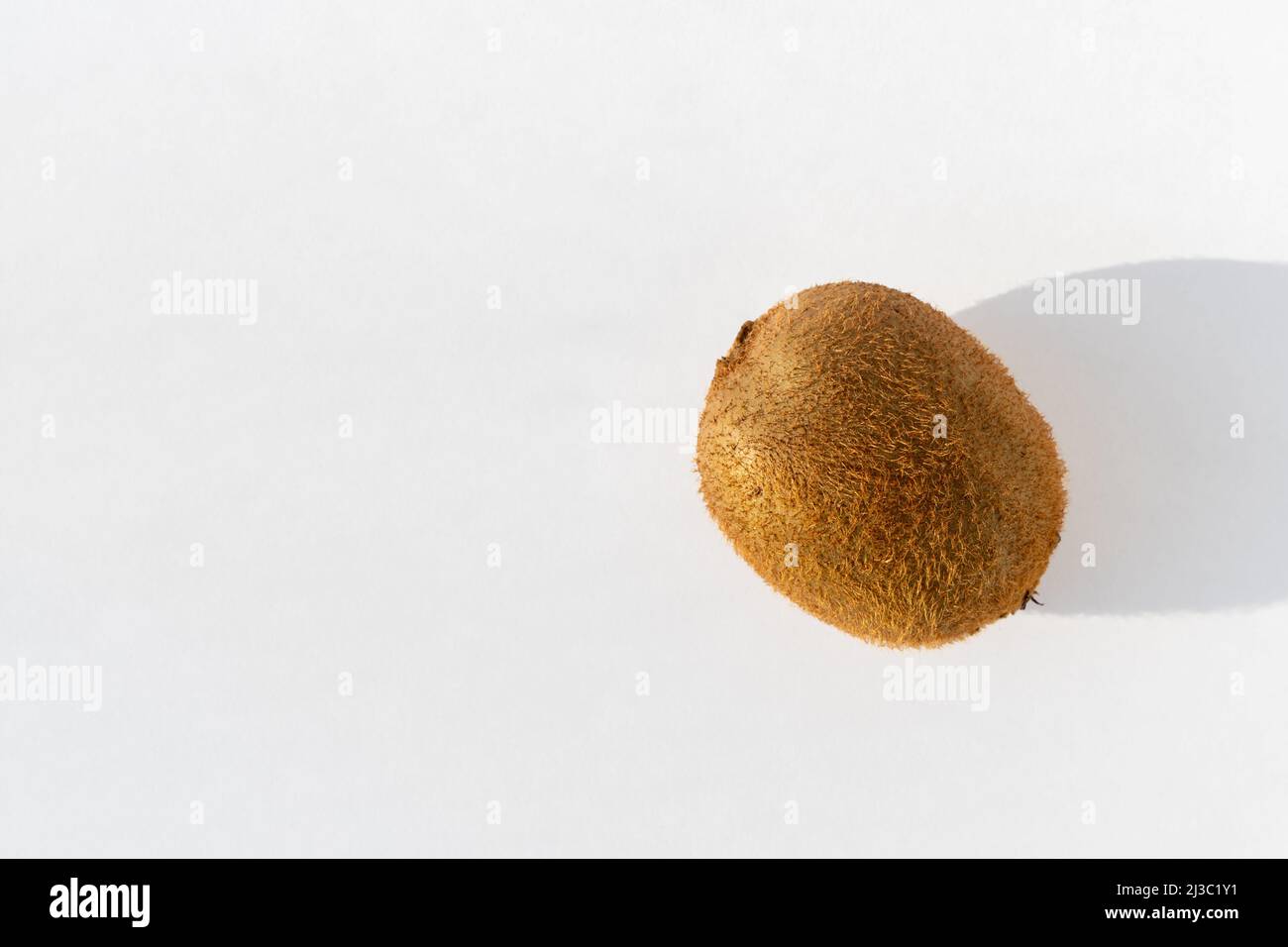 Ripe unpeeled kiwi fruit on a white background, copy space. Kiwi is a ...