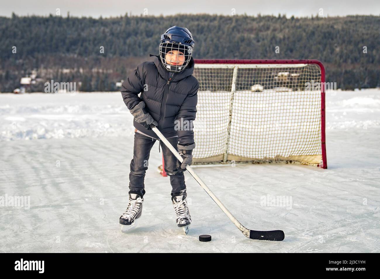 Boy playing hockey on a beautiful lake Stock Photo - Alamy