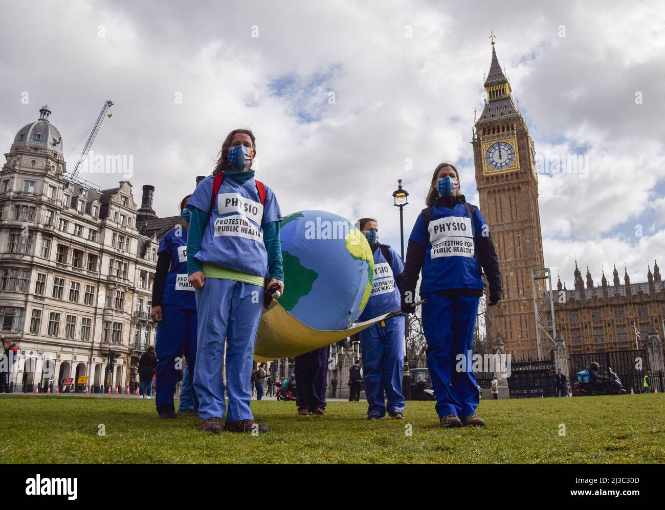 London, UK. 7th April 2022. Protesters carry a 'dying planet Earth' in ...