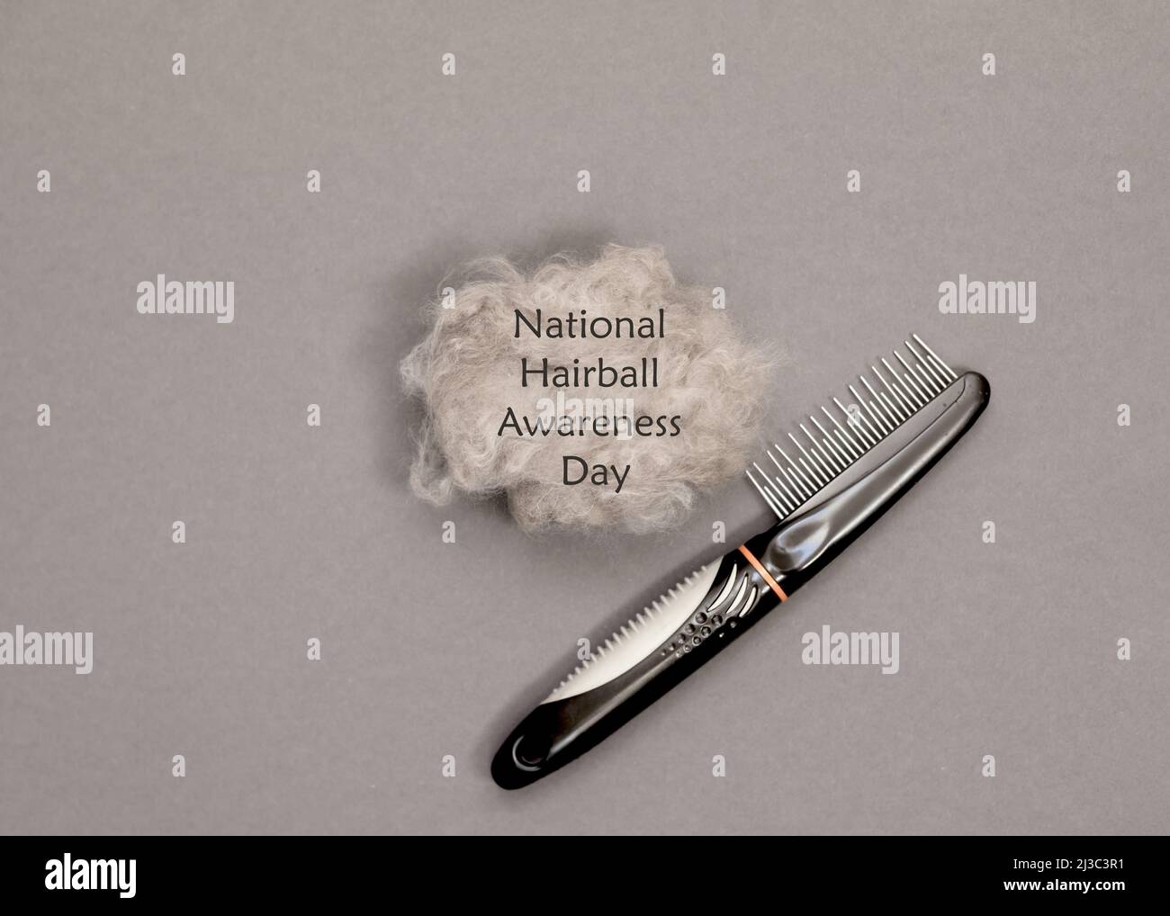 Grooming comb with metal teeth and a large ball of long hair on a gray ...