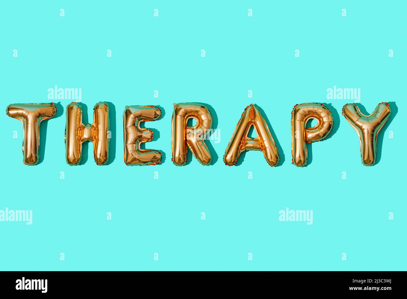 golden letter-shaped balloons forming the word therapy on a blue ...