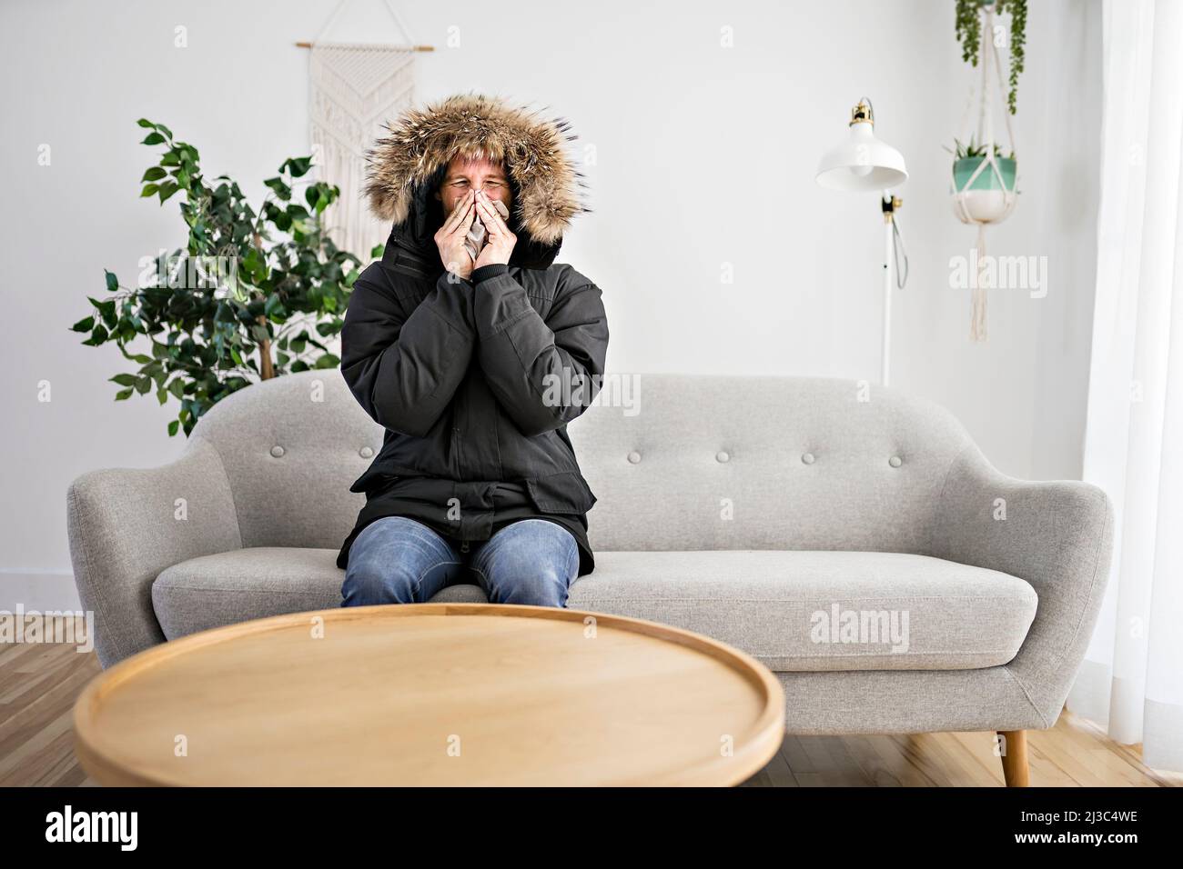 Man With Warm Clothing Feeling The Cold Inside House on the sofa Stock ...