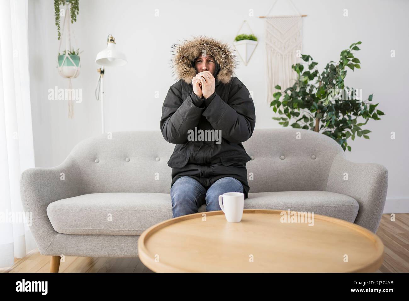 Man With Warm Clothing Feeling The Cold Inside House on the sofa Stock ...