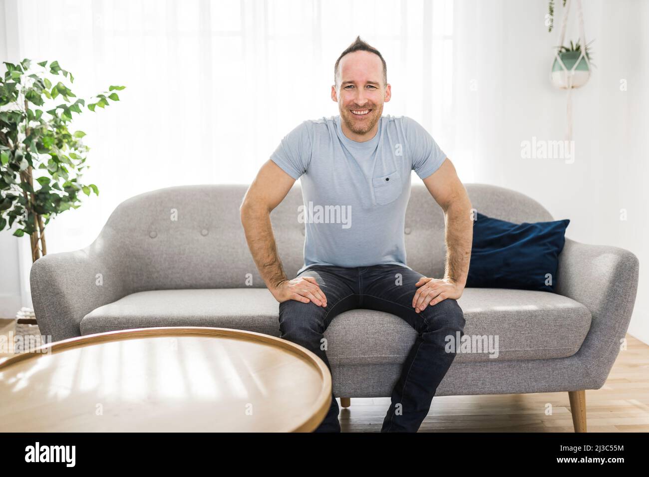 Smiling young man relaxing on sofa at home Stock Photo - Alamy