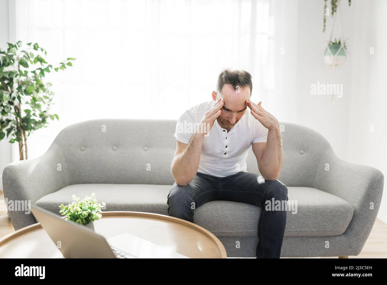 Frustrated handsome man with problem sitting on the couch at home Stock ...