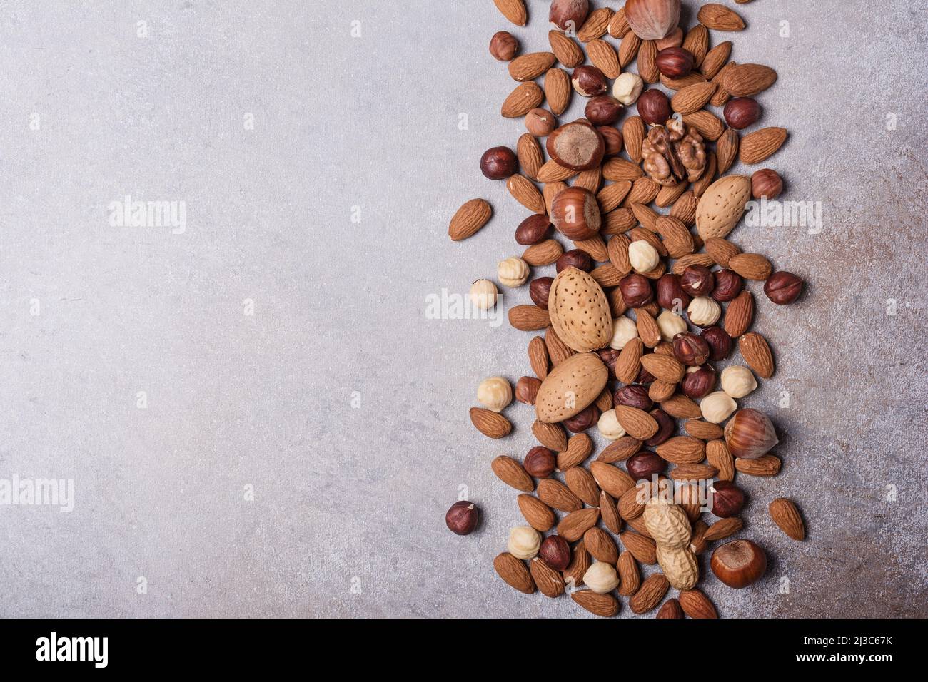 Top view of almond, hazelnut, walnut and peanut nuts in a row on grey ...