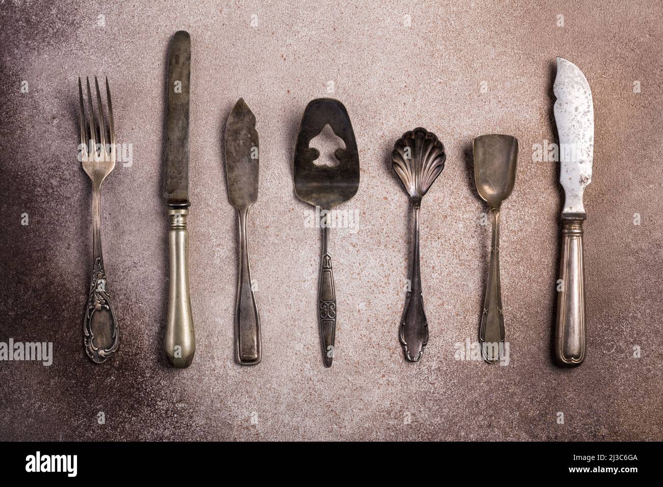 Top view of vintage silver cutlery or silverware on brown concrete ...