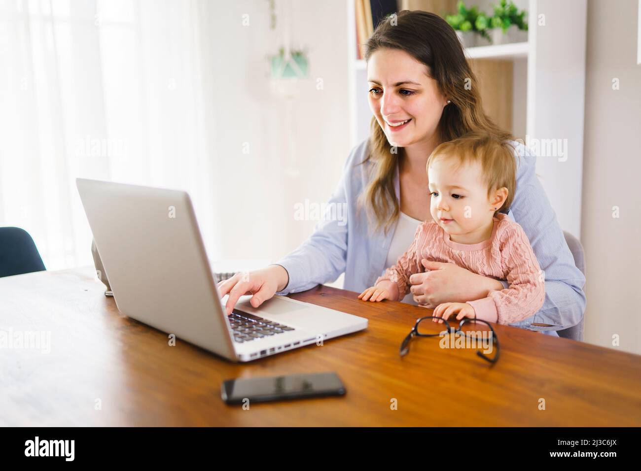 mother in kitchen home office with computer and her daugher Stock Photo ...
