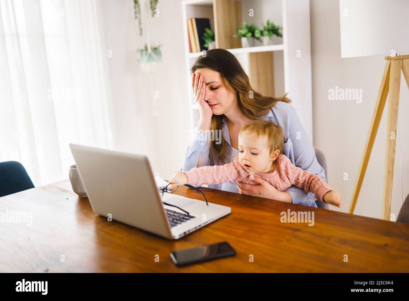 sad and frustrated mother in kitchen home office with computer and her ...