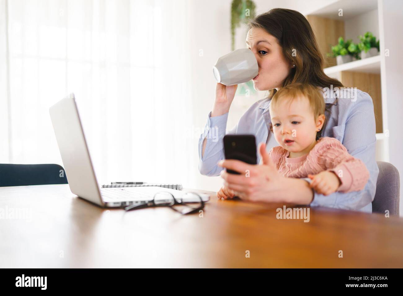 mother in kitchen home office with computer and her daugher Stock Photo ...