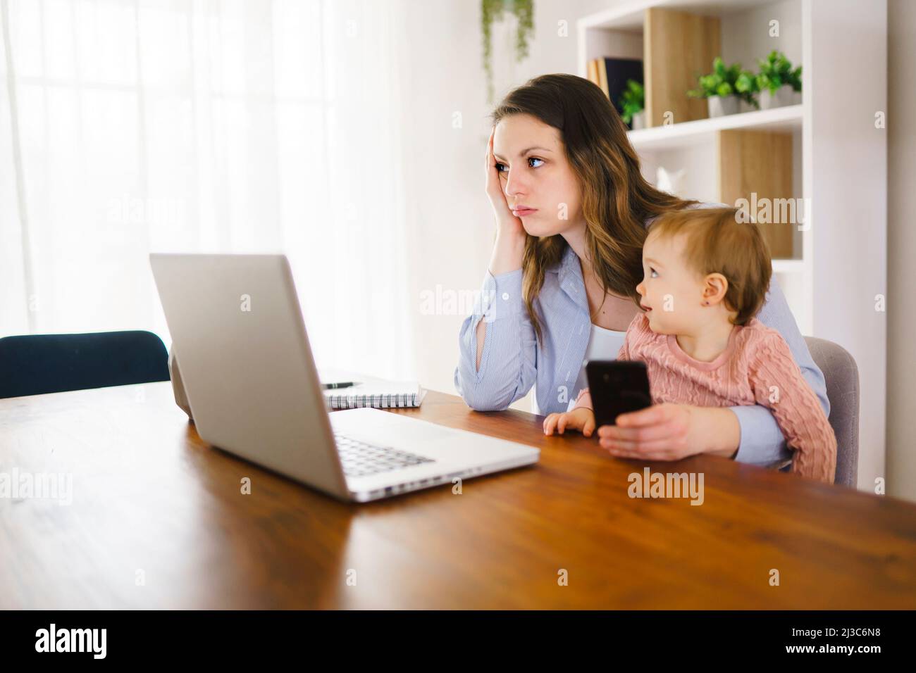 sad and frustrated mother in kitchen home office with computer and her ...