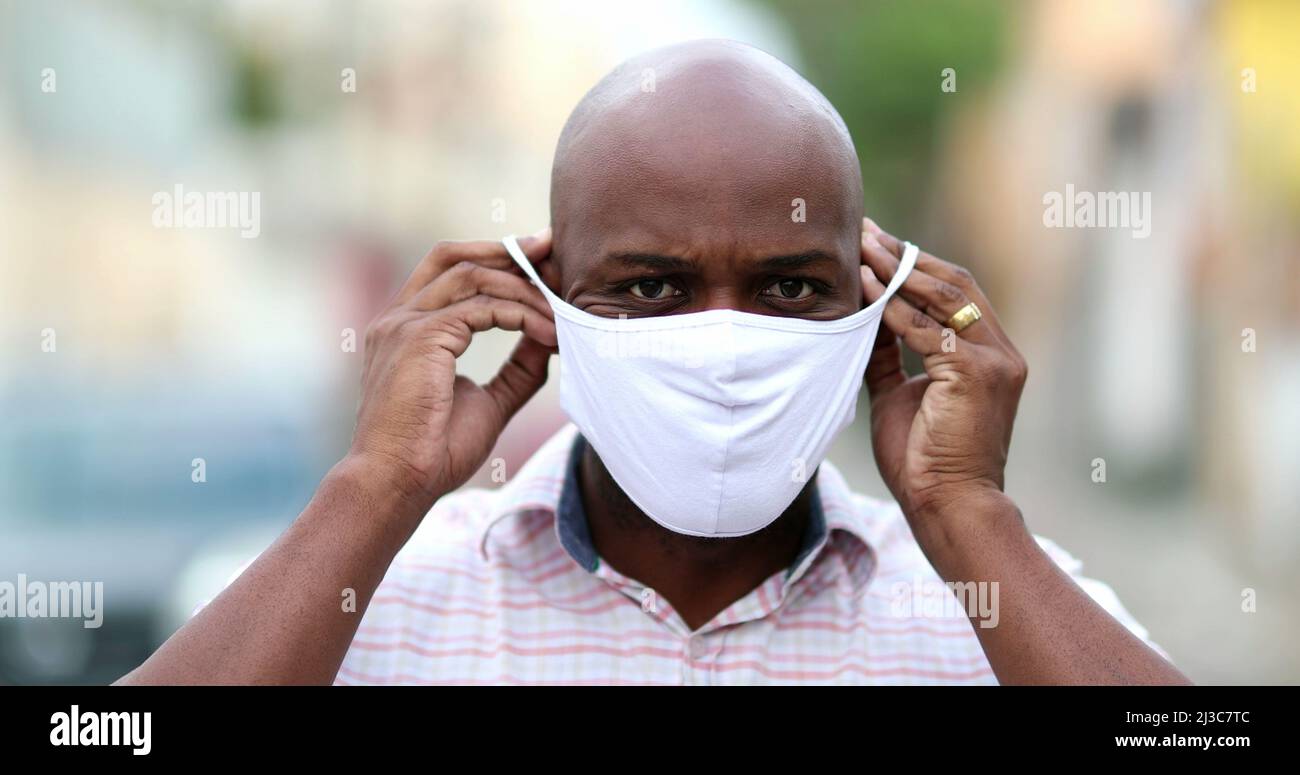 African man putting covid-19 face mask outside in urban street Stock ...