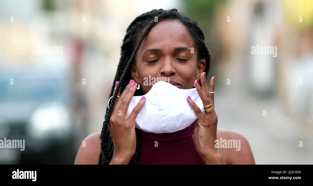 African woman removing covid-19 face mask outside in street smiling and ...