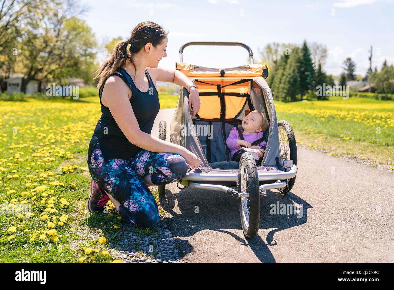 Beautiful young family with baby in jogging stroller running outside in ...