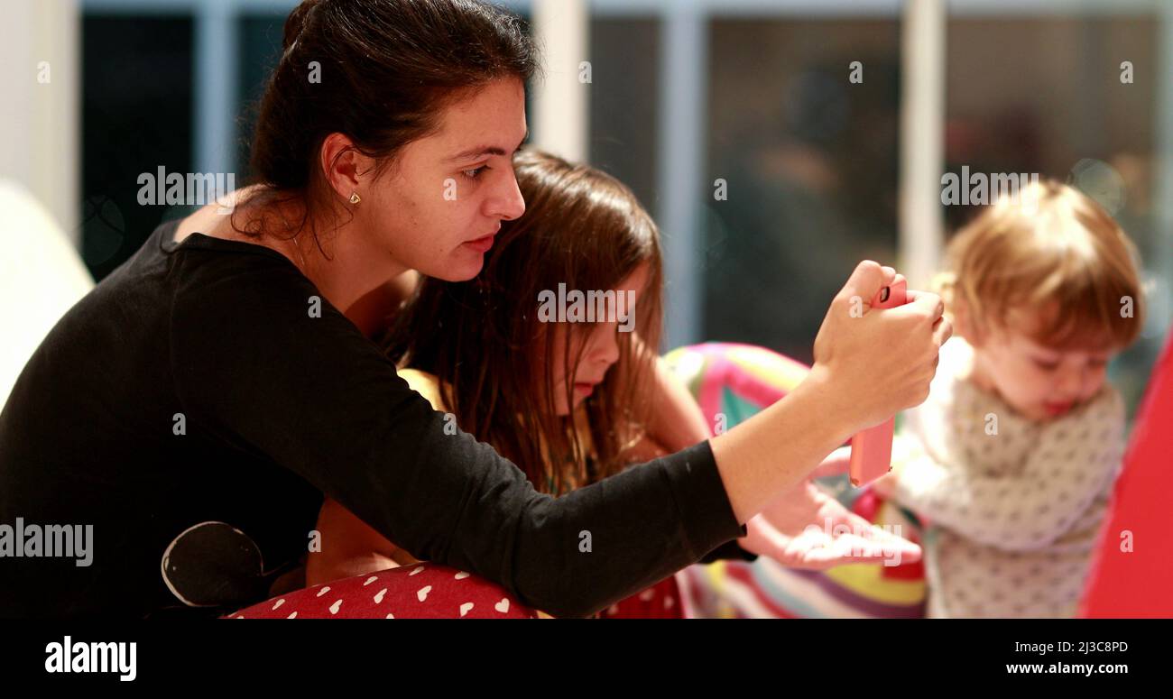 Mother talking on video with phone, candid parent and child speak with ...