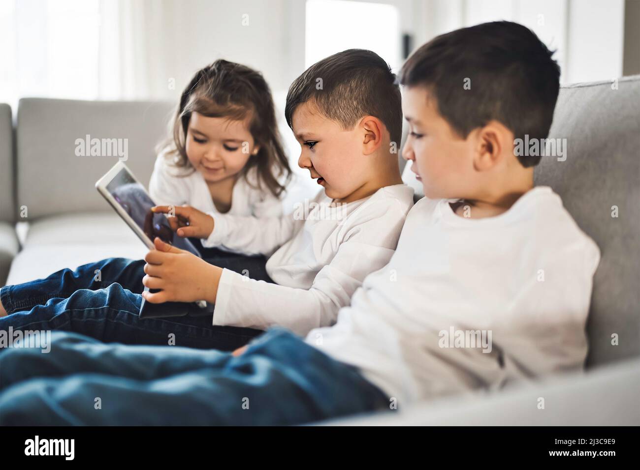 Childs relaxing with their tablets on a comfortable sofa at home Stock ...