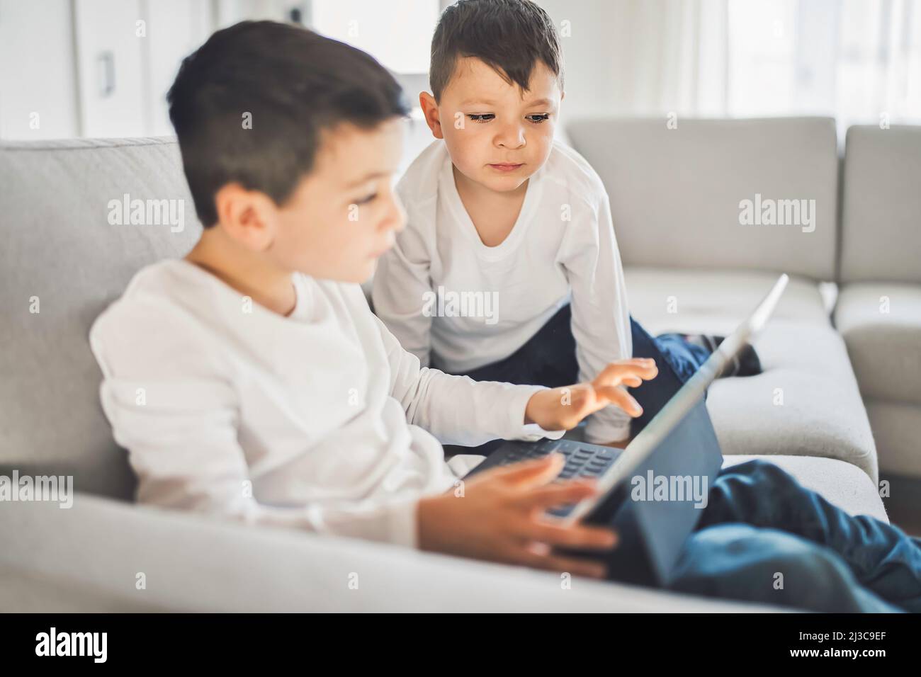Childs relaxing with their tablets on a comfortable sofa at home Stock ...