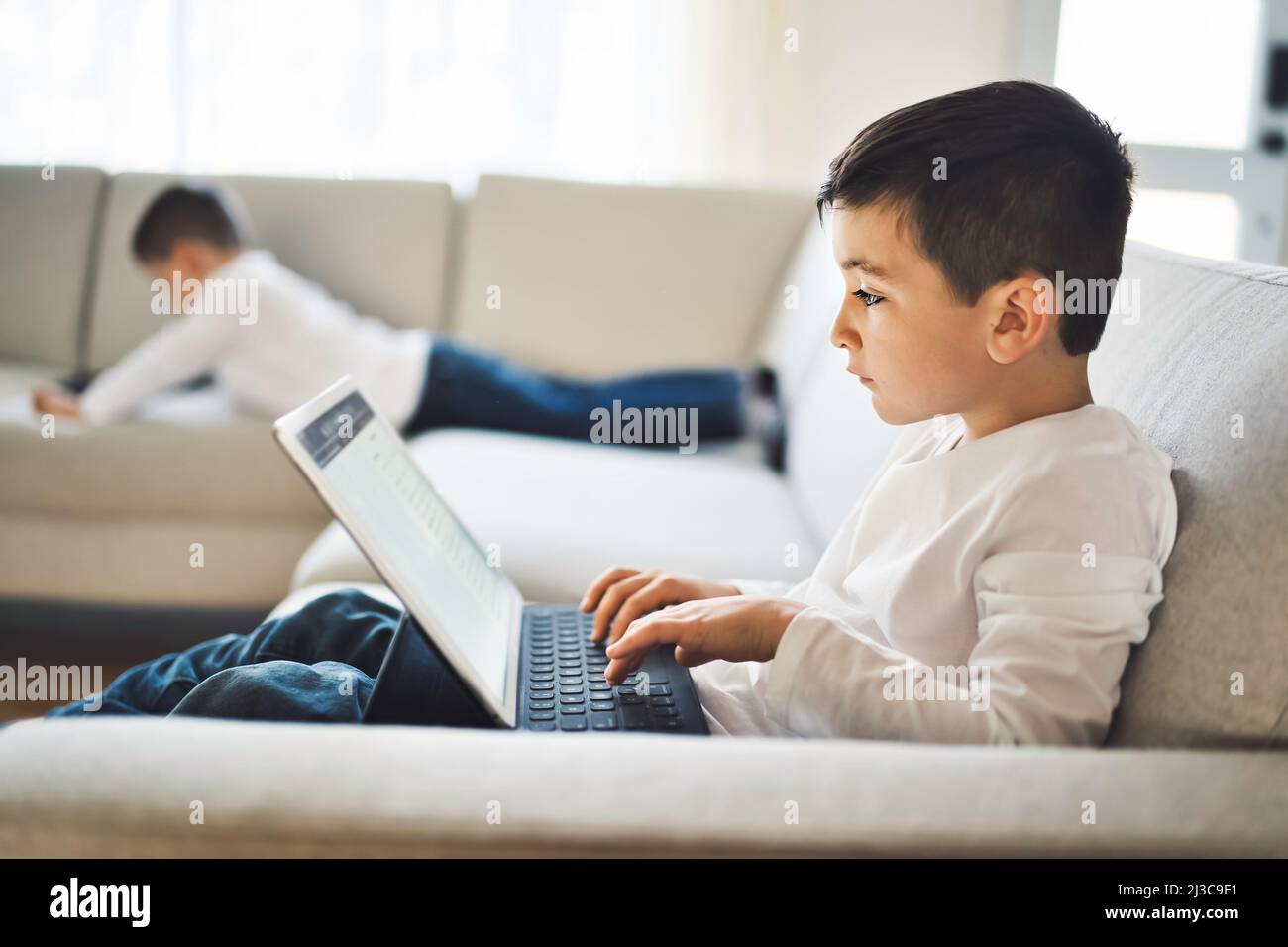 Childs relaxing with their tablets on a comfortable sofa at home Stock ...