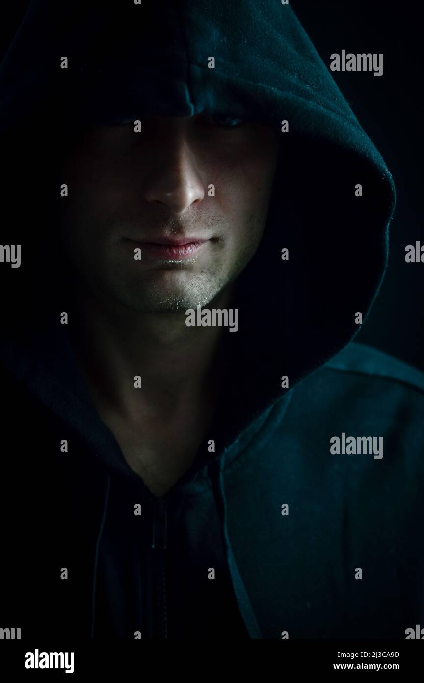 Portrait of a young man with a hood covering his head and keeping his ...