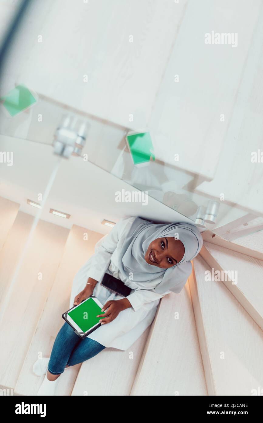 Young african modern muslim woman using tablet computer while sitting ...