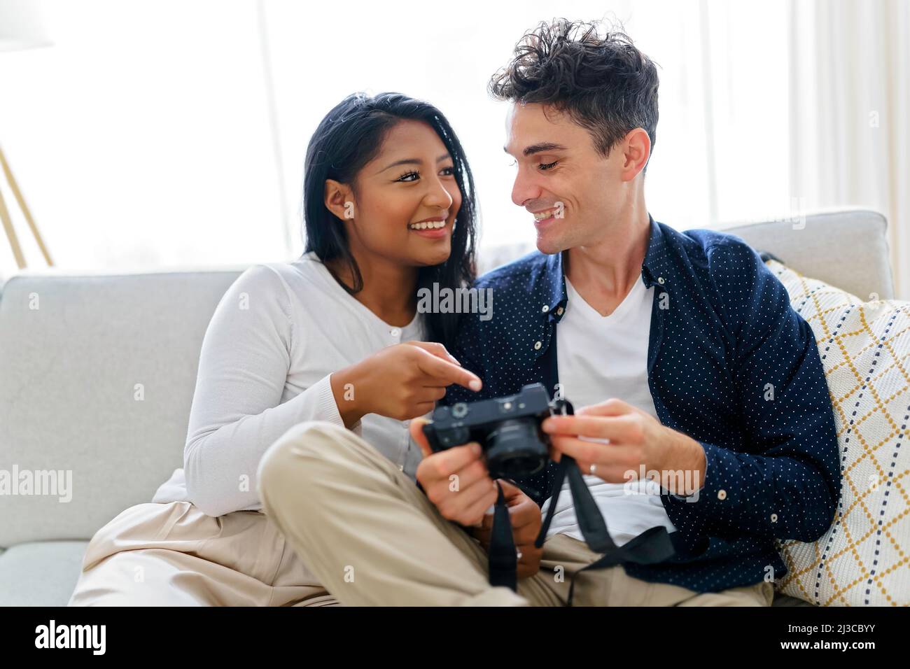 european couple in living room having fun on the sofa with photo camera ...