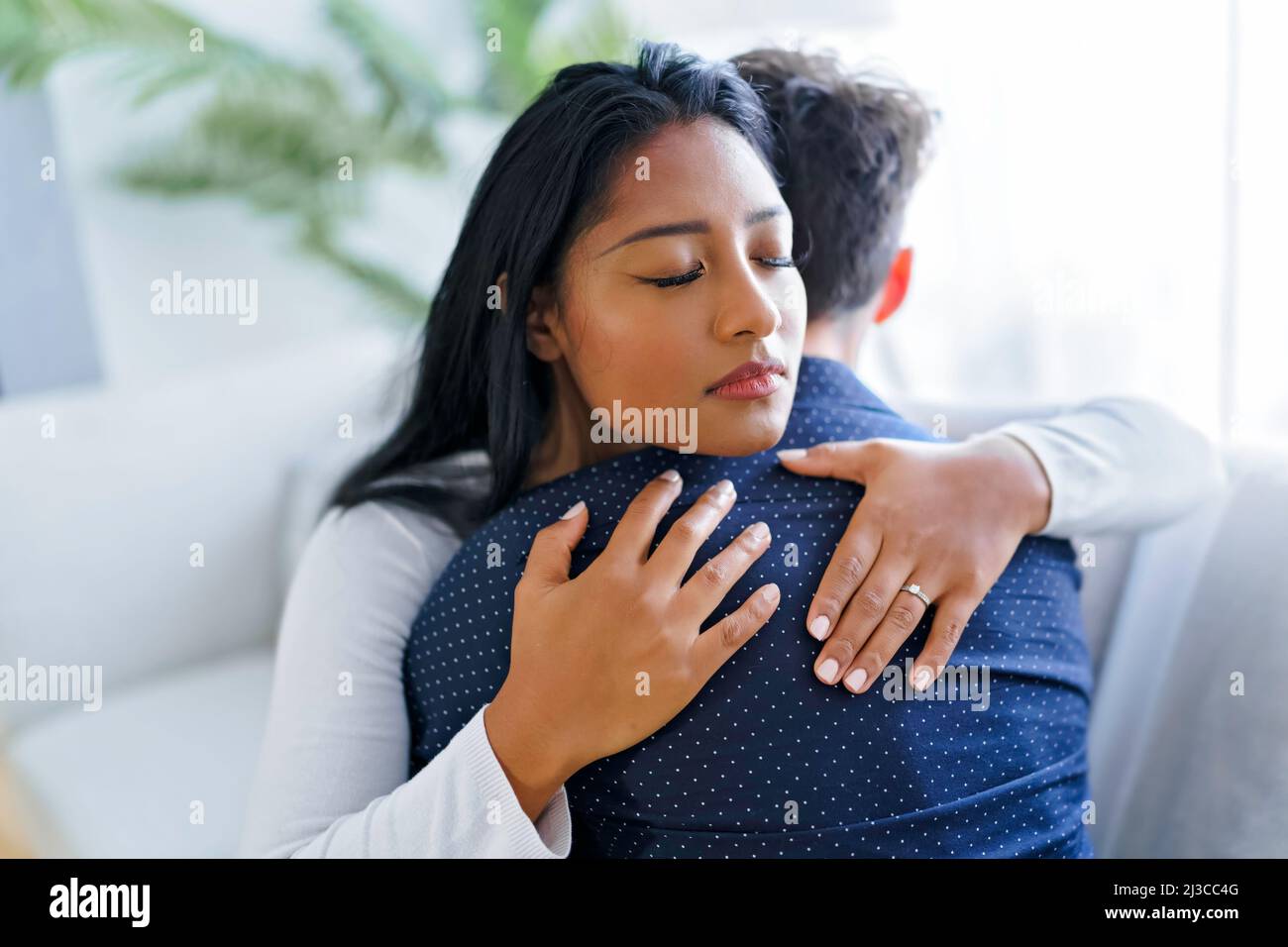 Attractive couple cuddling on the couch at home in the living room ...