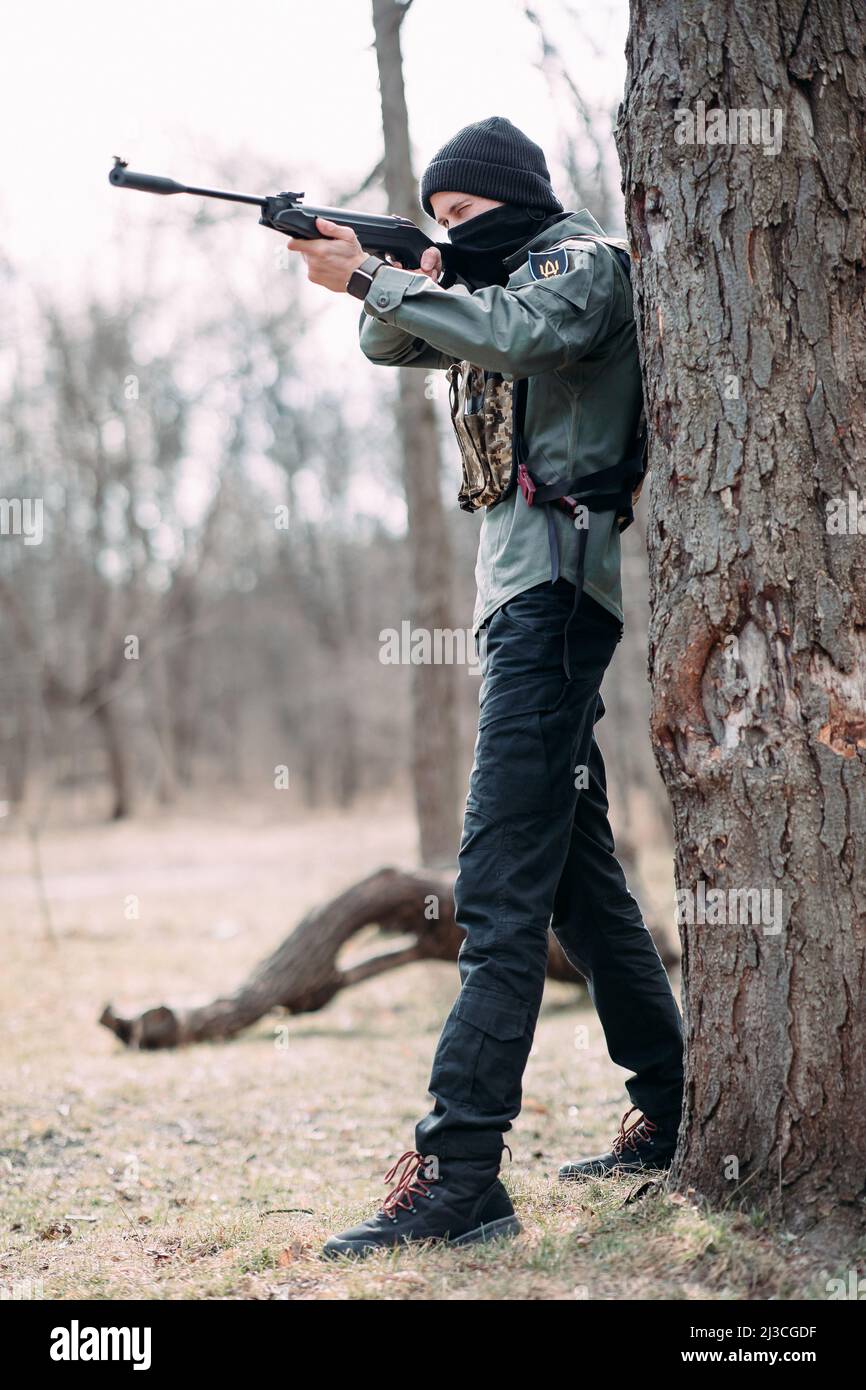 Young man practices and aims from pump gun weared in body armor and ...