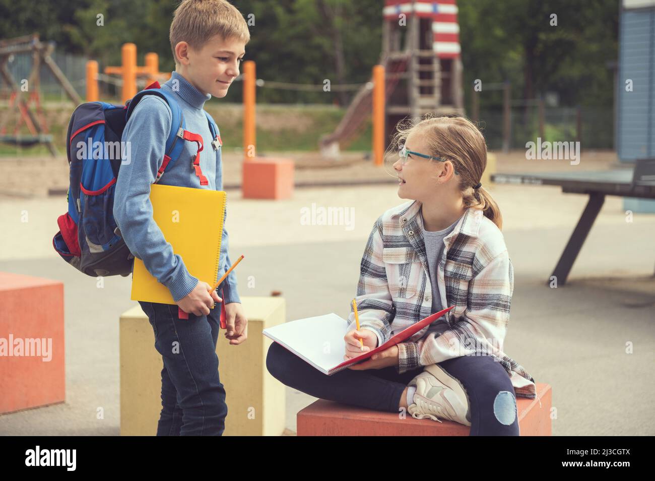 Male and female classmates studying in the school yard after classes ...