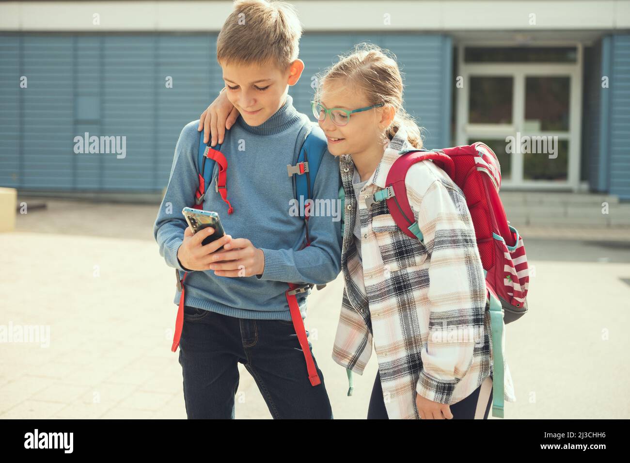 Teen schoolchildren playing with cell phone in school yard after ...