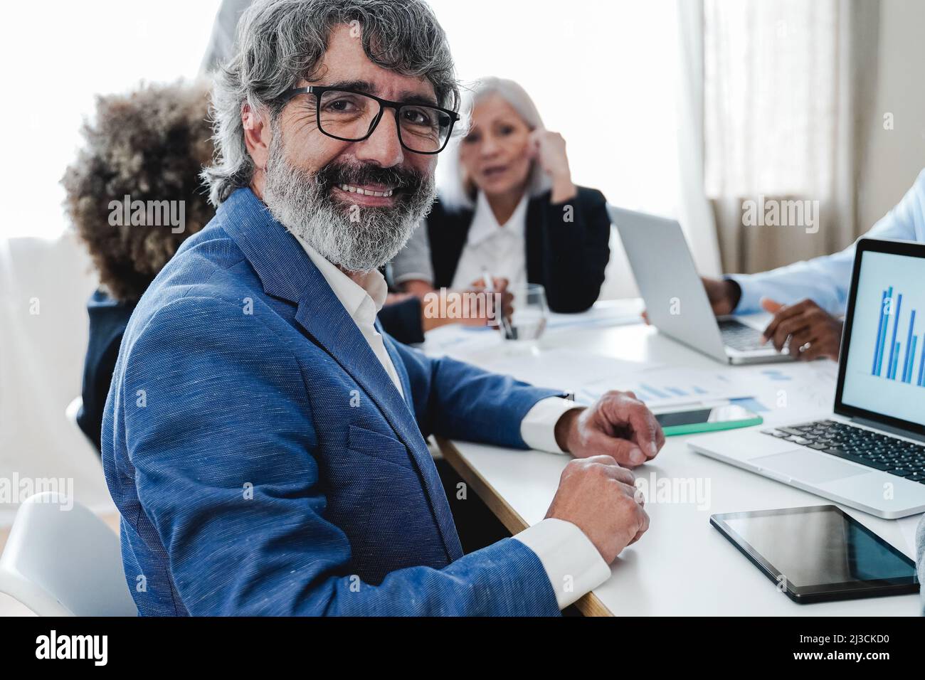 Senior business man smiling at camera while working with colleagues ...