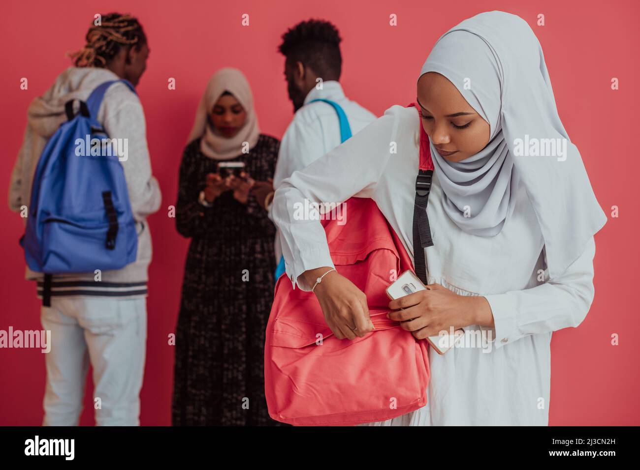 A group of African Muslim students with backpacks posing on a pink ...