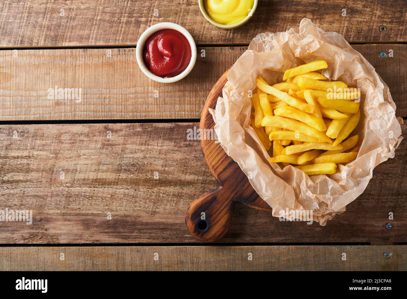 French fries. Tasty French fries server on parchment paper on wooden ...