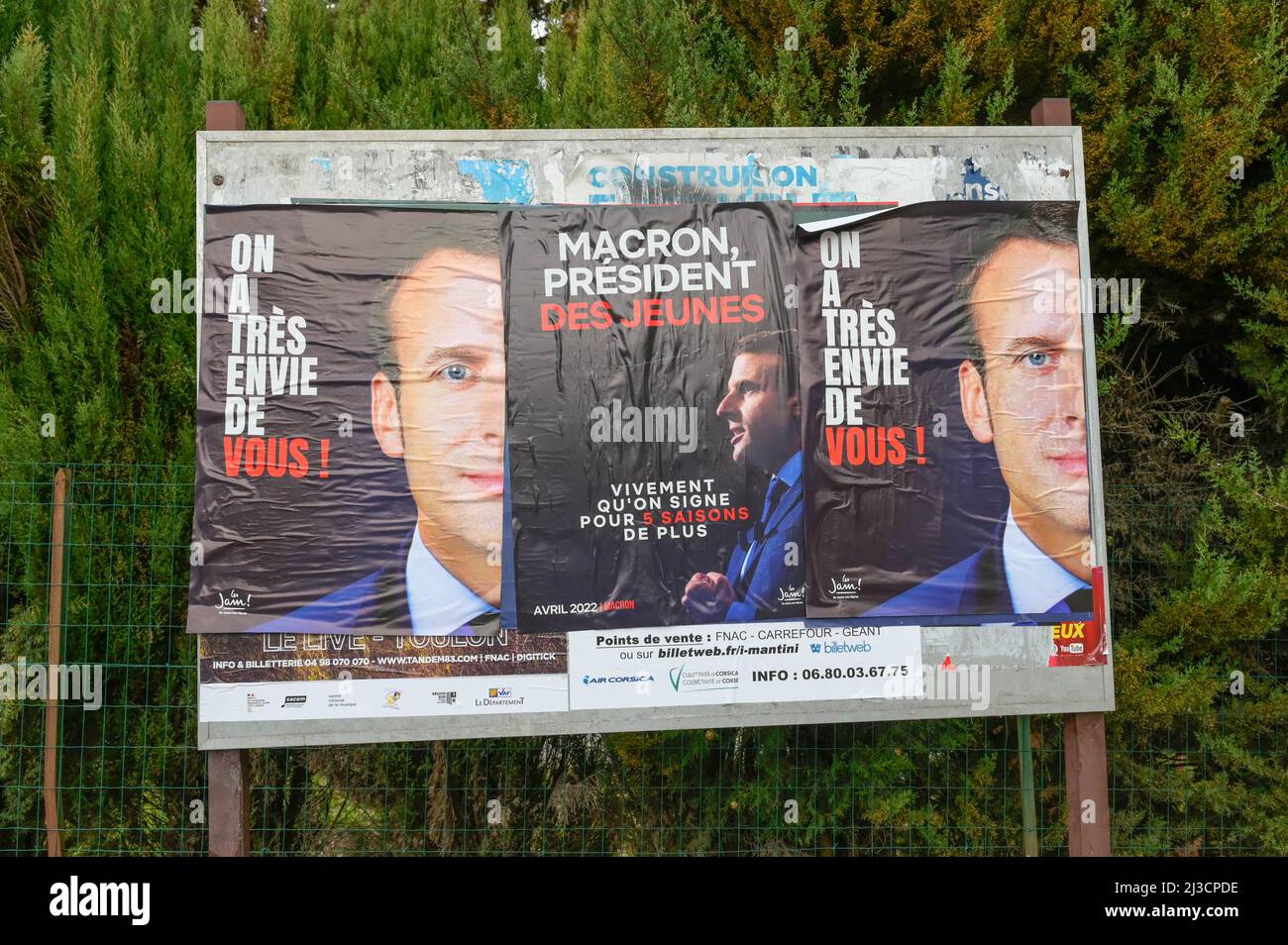 Three campaign posters of Emmanuel Macron are stuck on a billboard in ...