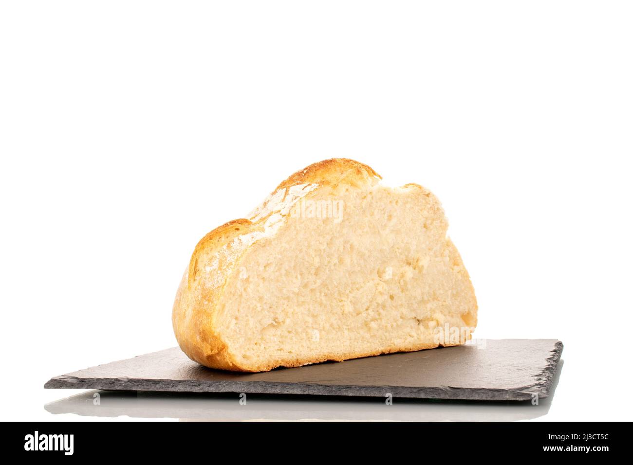 One half of a loaf of fresh fragrant white wheat bread on a slate stone ...