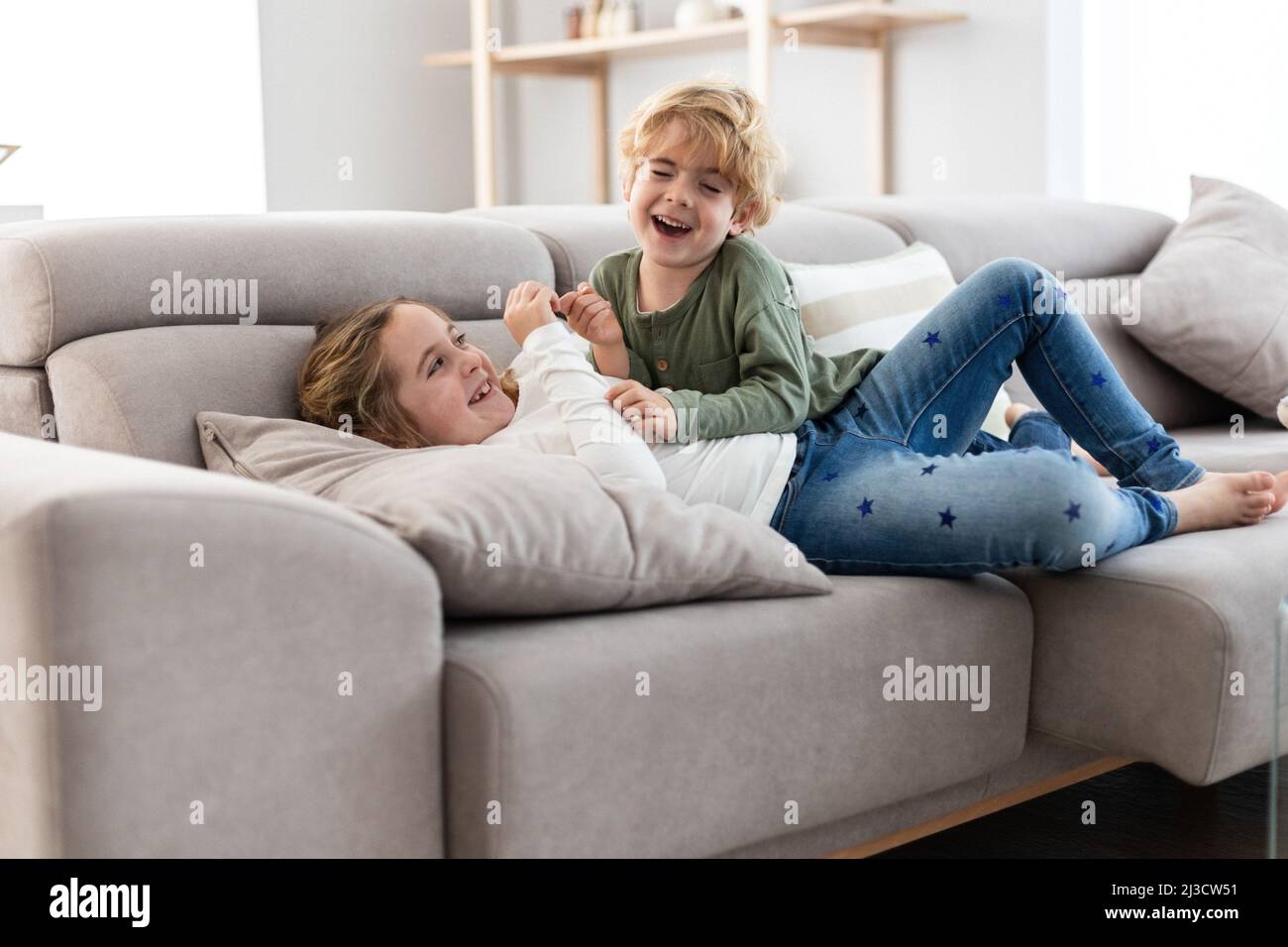 Positive children in casual wear playing together while lying on ...